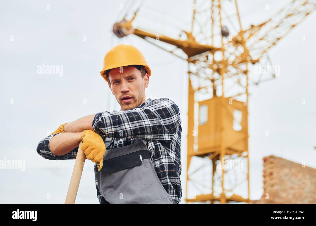 Using shovel with wooden holder. Construction worker in uniform and ...