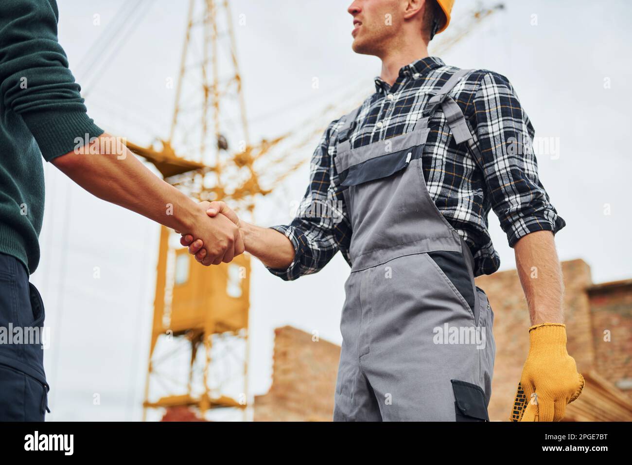 Making handshake. Two construction workers in uniform and safety ...