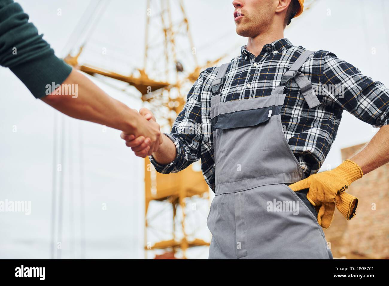 Making handshake. Two construction workers in uniform and safety ...