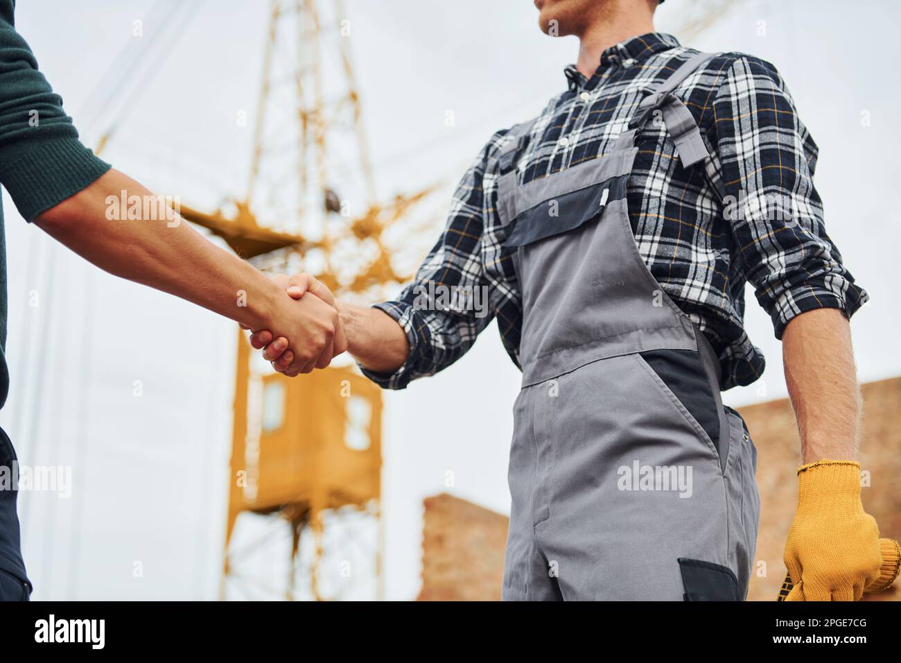 Making handshake. Two construction workers in uniform and safety ...