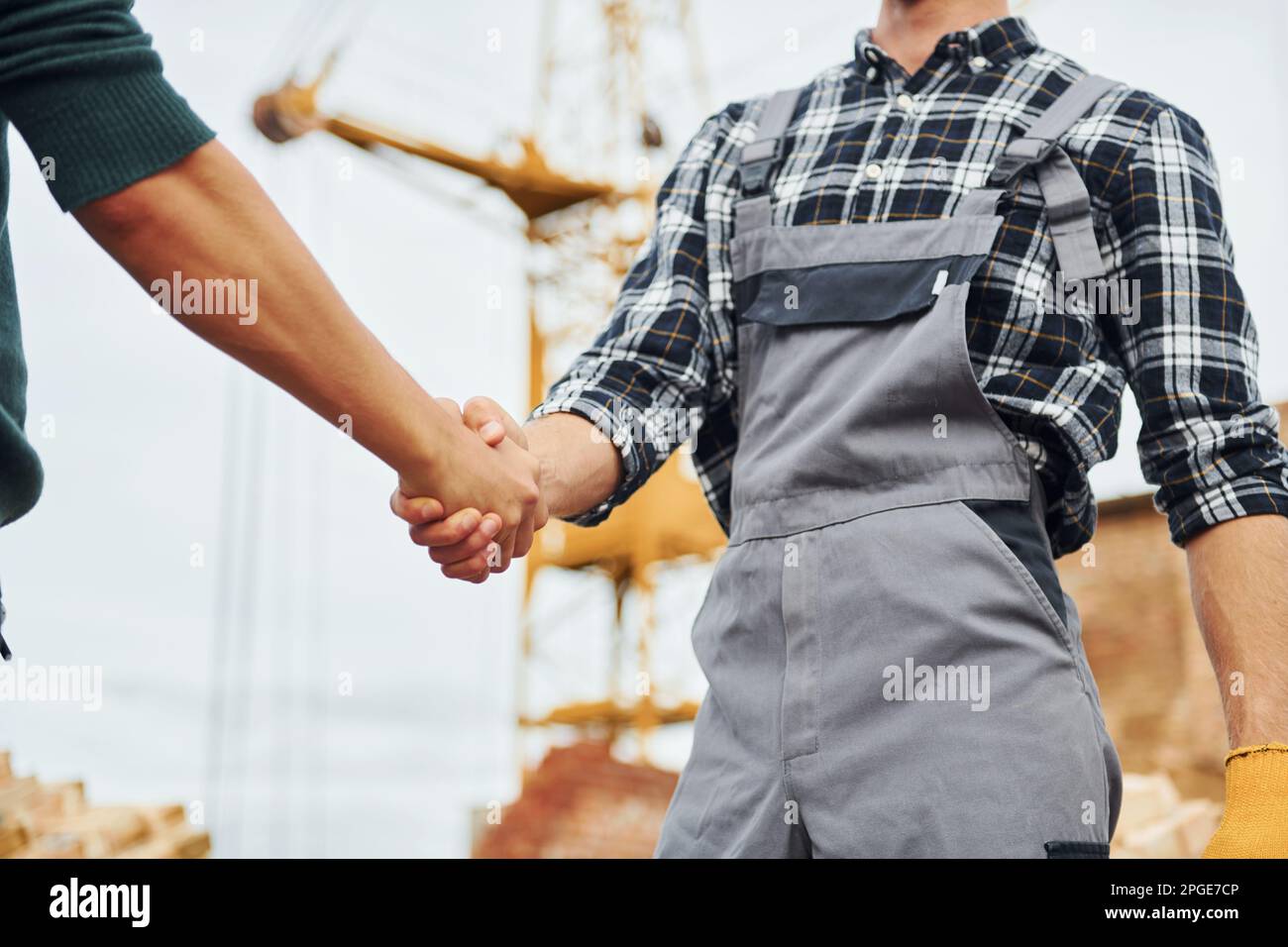 Making handshake. Two construction workers in uniform and safety ...