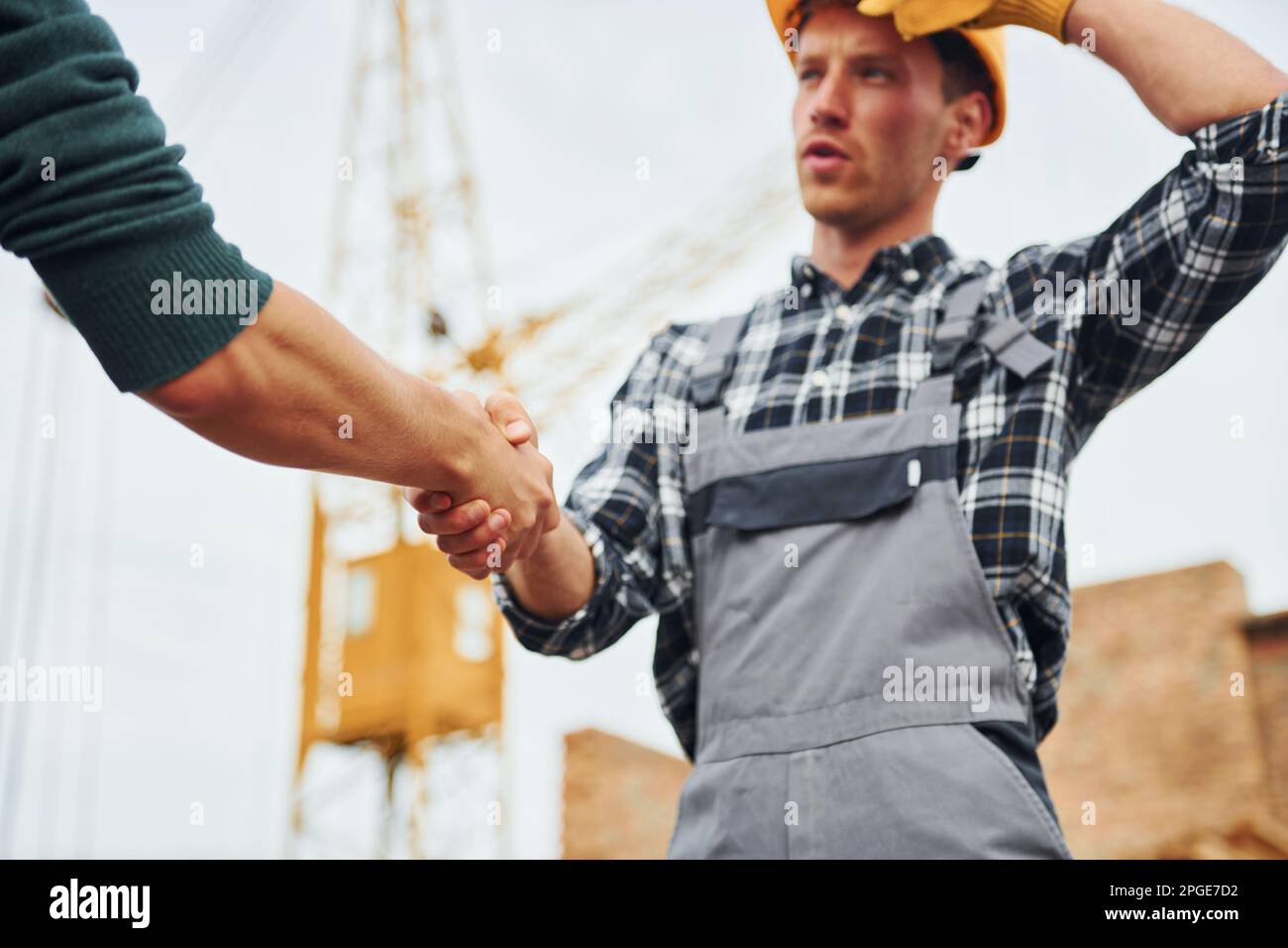 Making handshake. Two construction workers in uniform and safety ...