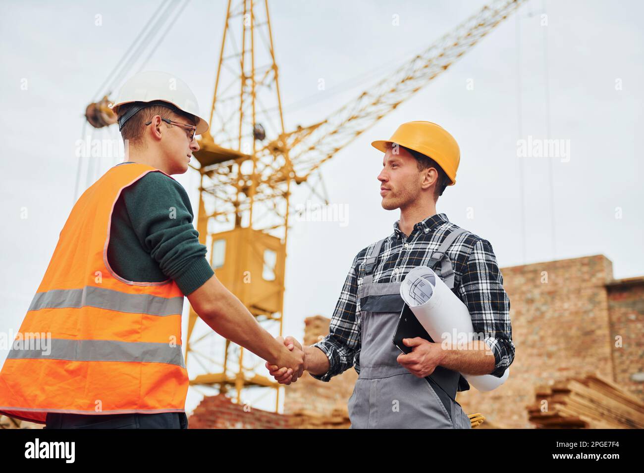 Agreement is successful. Two construction workers in uniform and safety ...