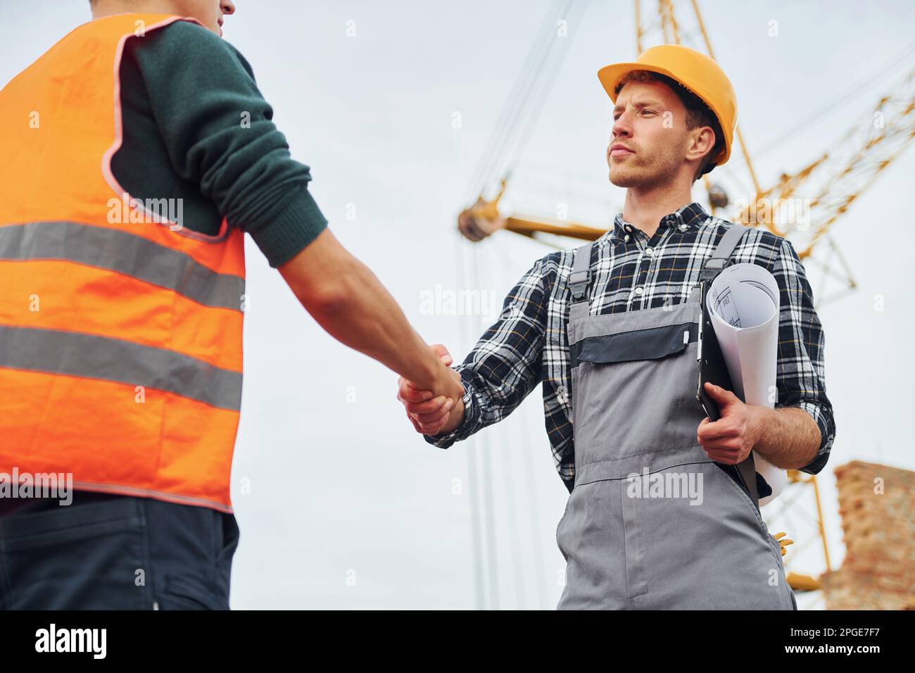 Making handshake. Two construction workers in uniform and safety ...