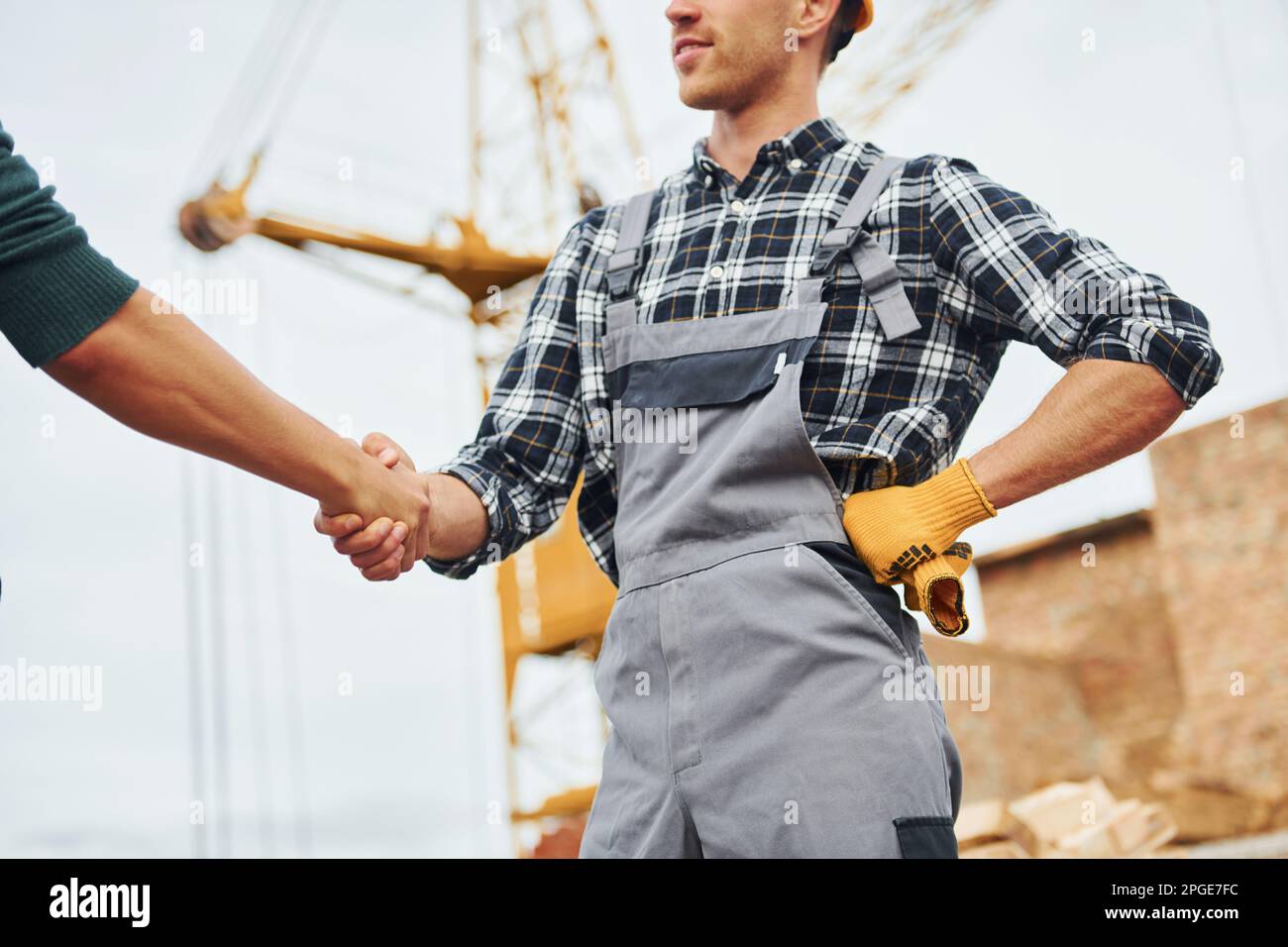 Making handshake. Two construction workers in uniform and safety ...