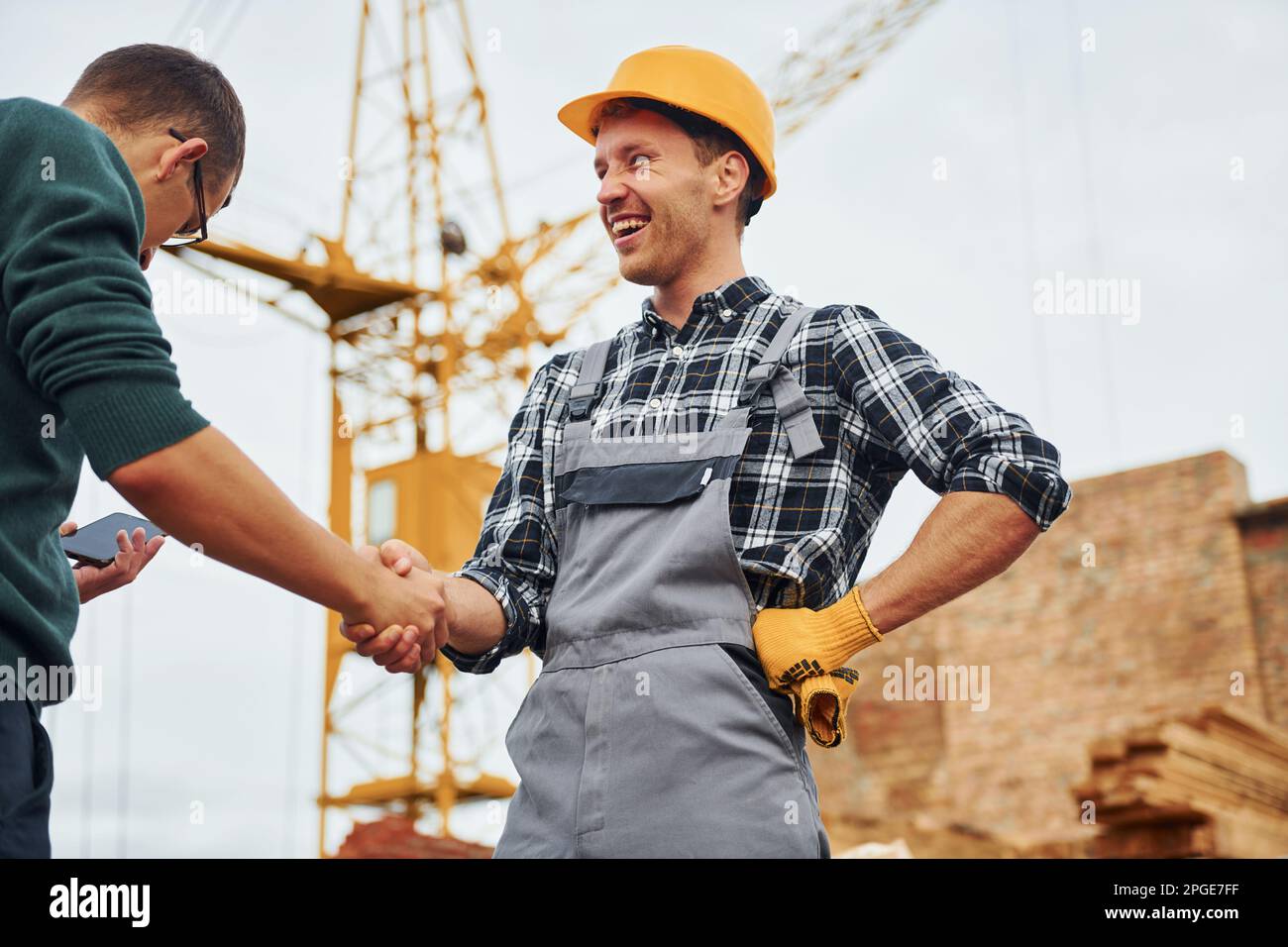 Making handshake. Two construction workers in uniform and safety ...