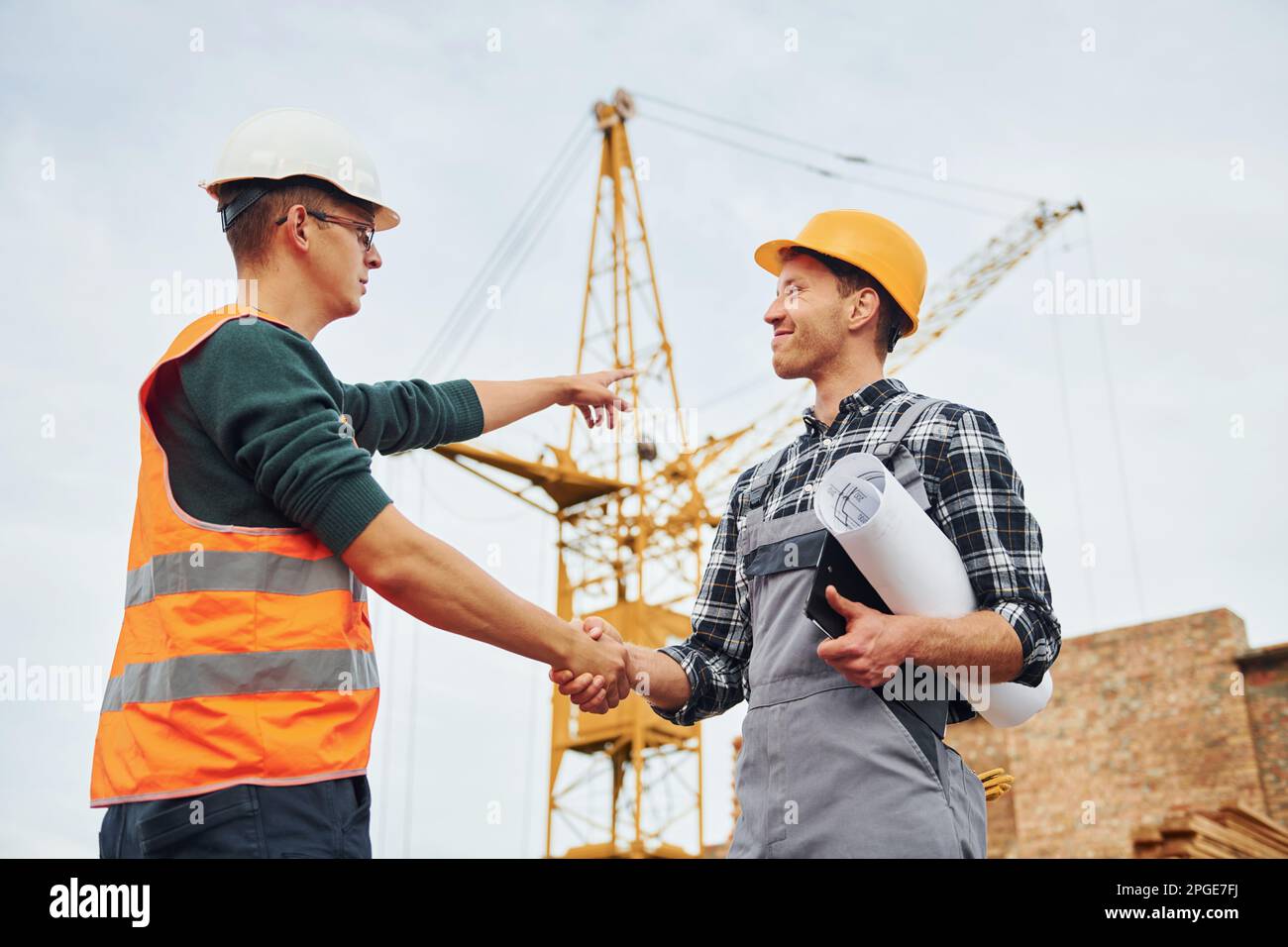 Making handshake. Two construction workers in uniform and safety ...