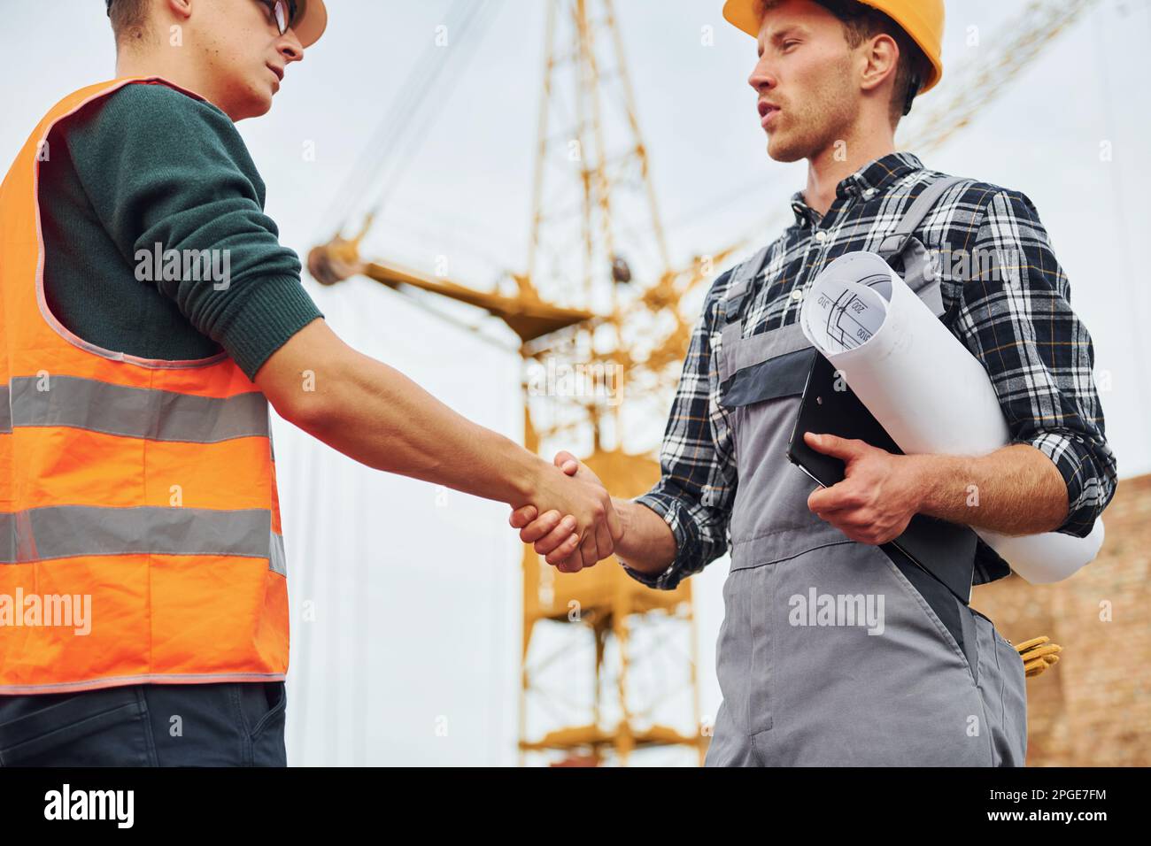 Making handshake. Two construction workers in uniform and safety ...