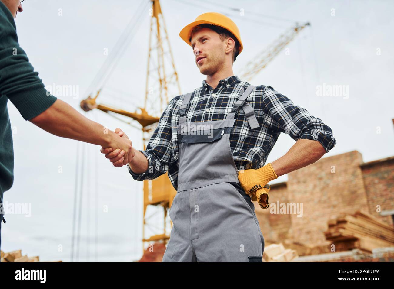 Making handshake. Two construction workers in uniform and safety ...
