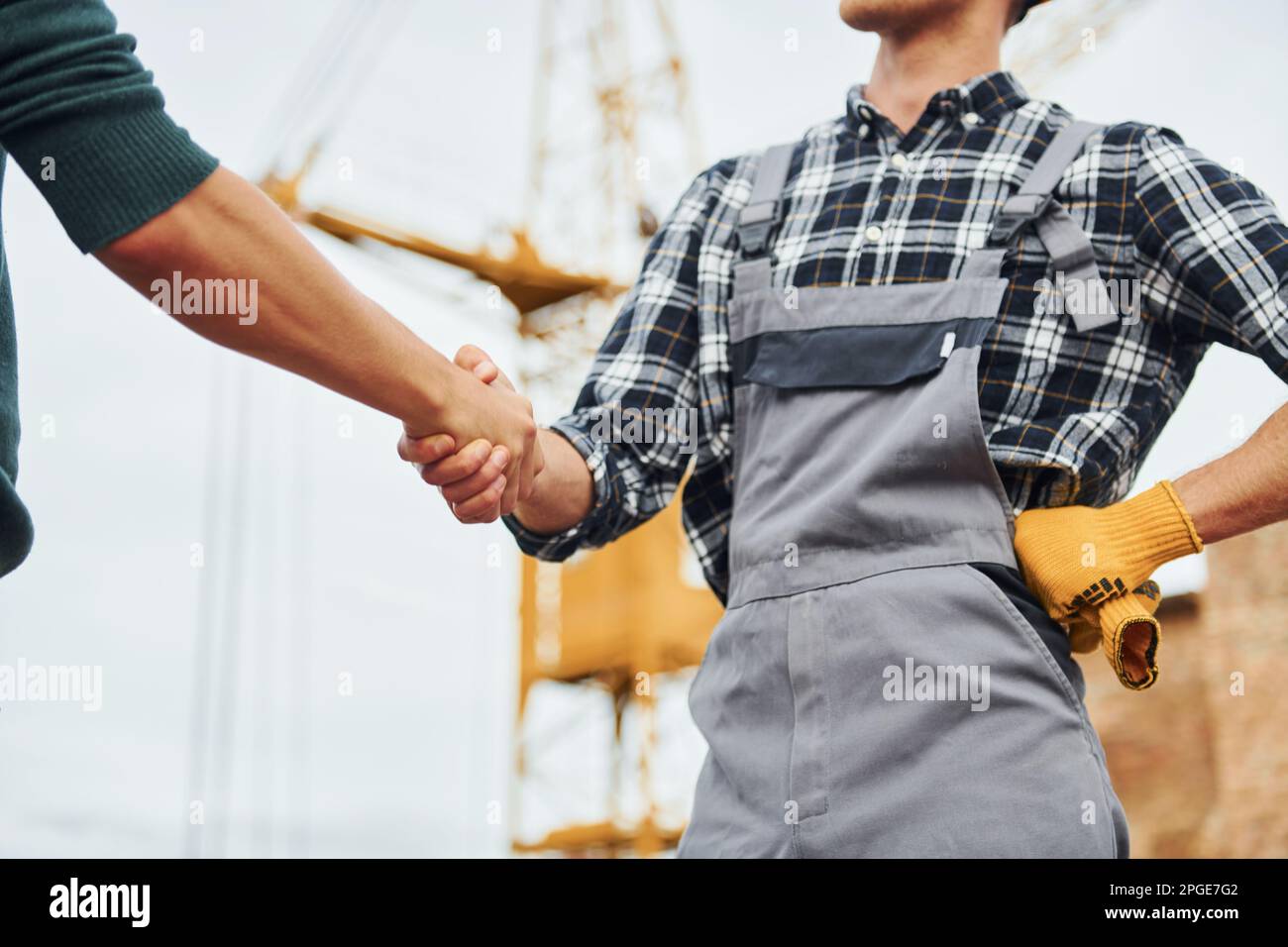 Making handshake. Two construction workers in uniform and safety ...