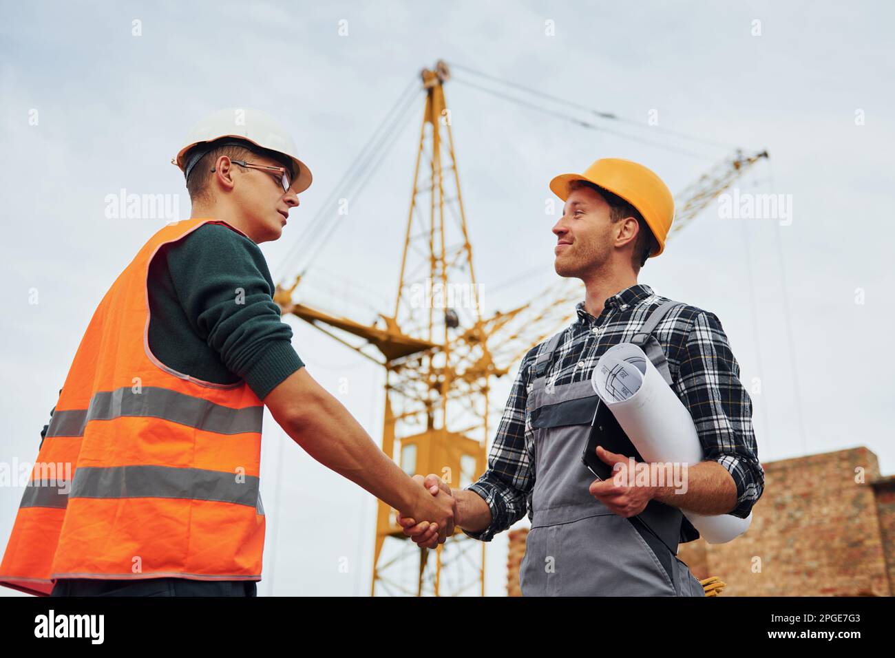 Making handshake. Two construction workers in uniform and safety ...