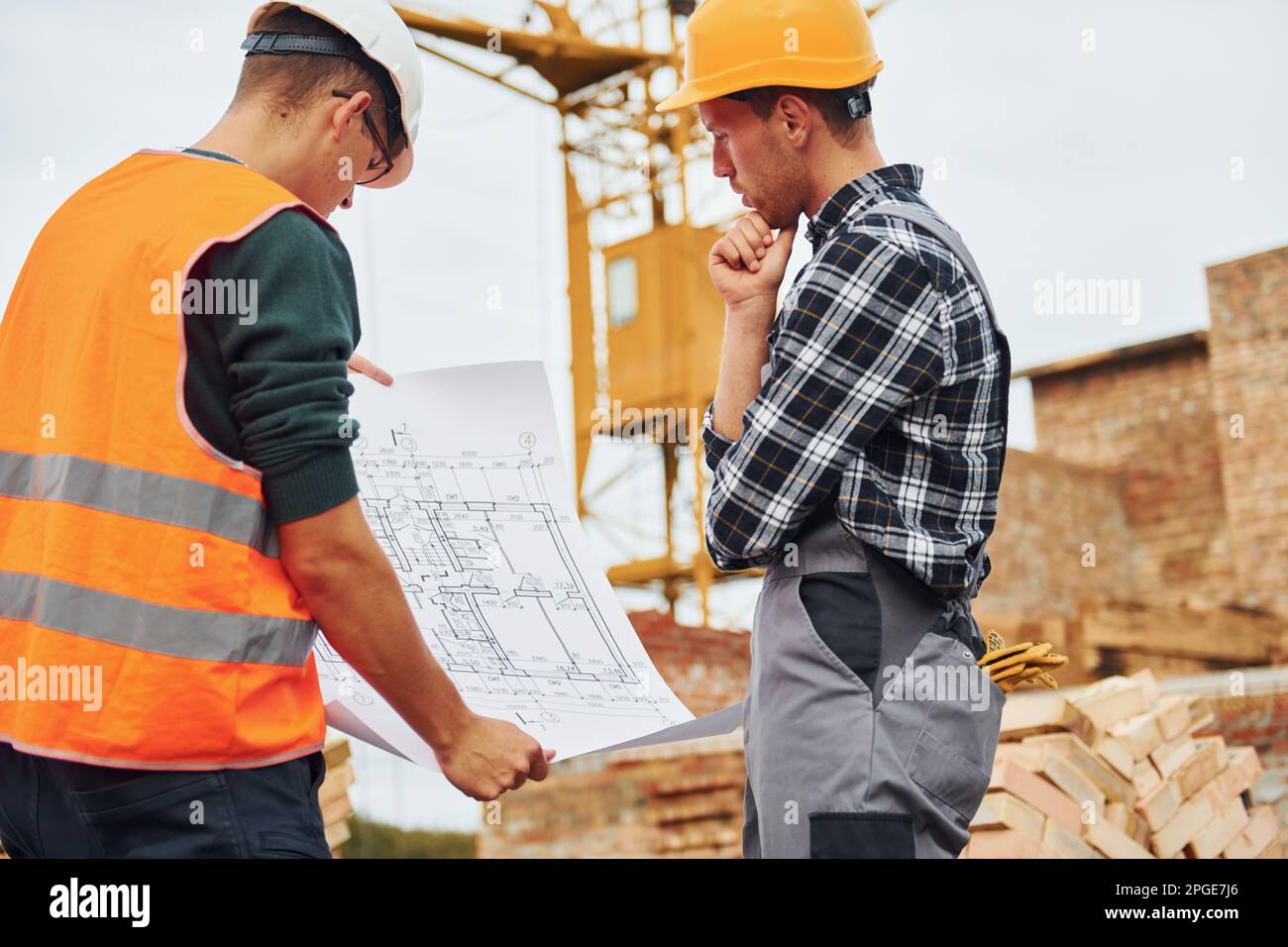 Using paper document with plan on it. Two construction workers in ...