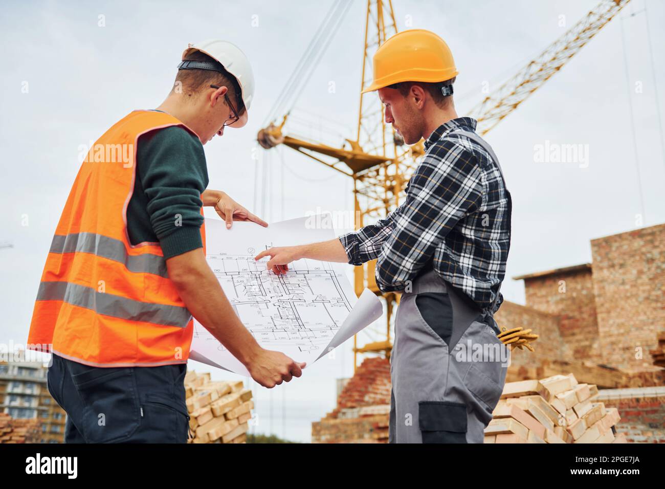 Using paper document with plan on it. Two construction workers in ...