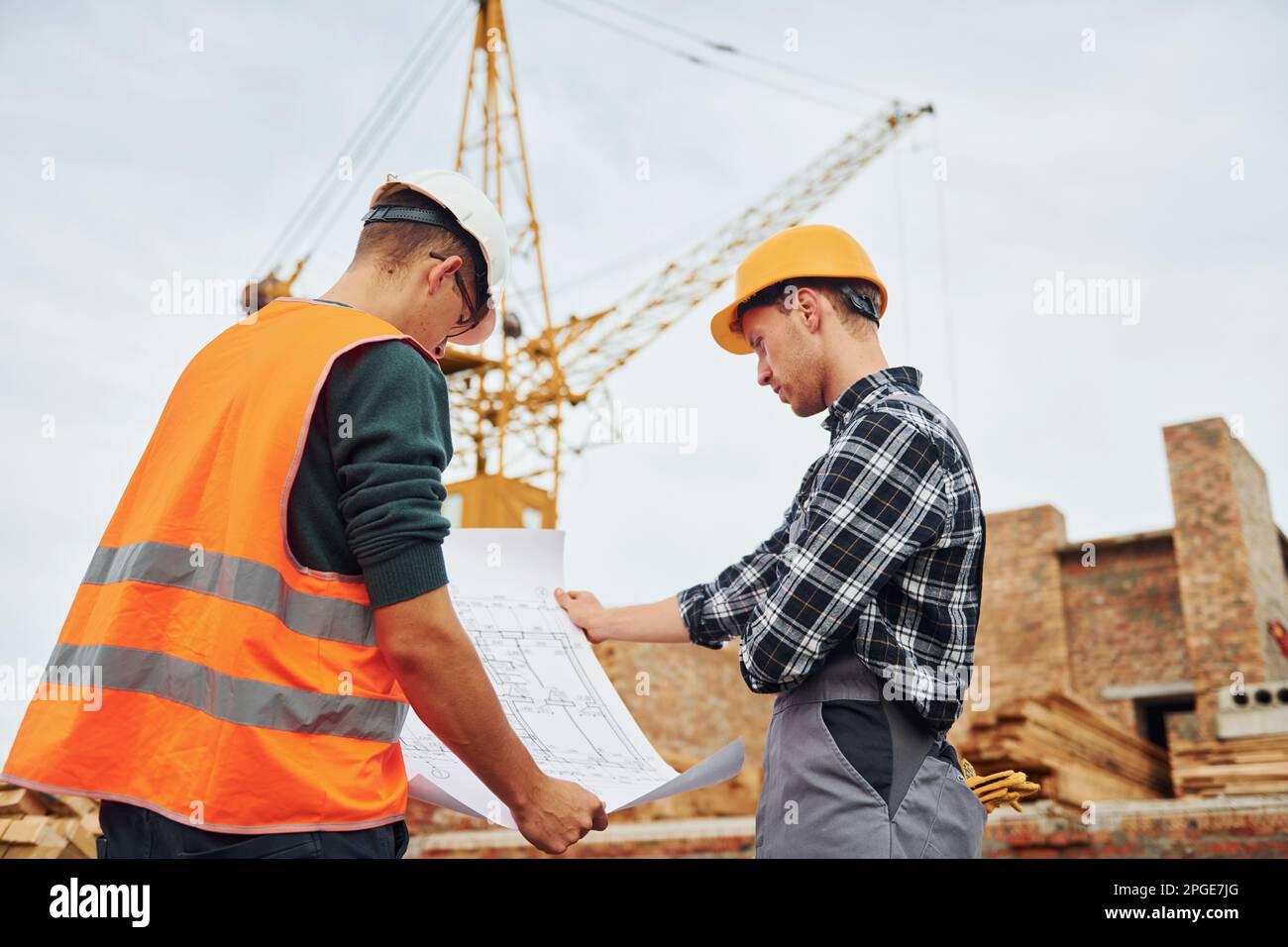 Using paper document with plan on it. Two construction workers in ...