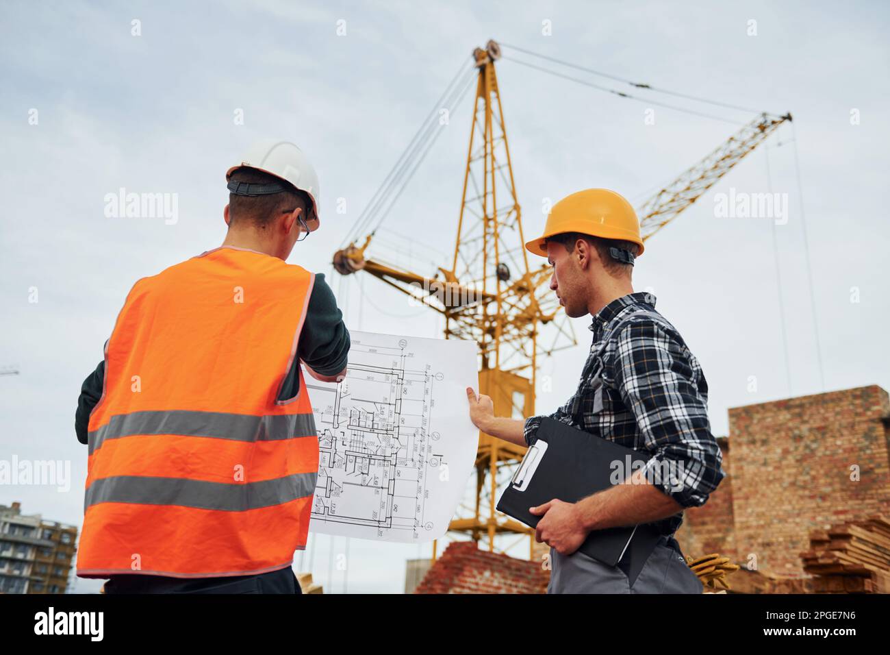 Using paper document with plan on it. Two construction workers in ...