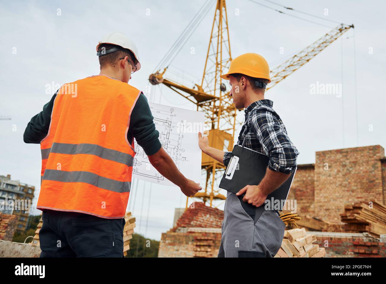 Using paper document with plan on it. Two construction workers in ...