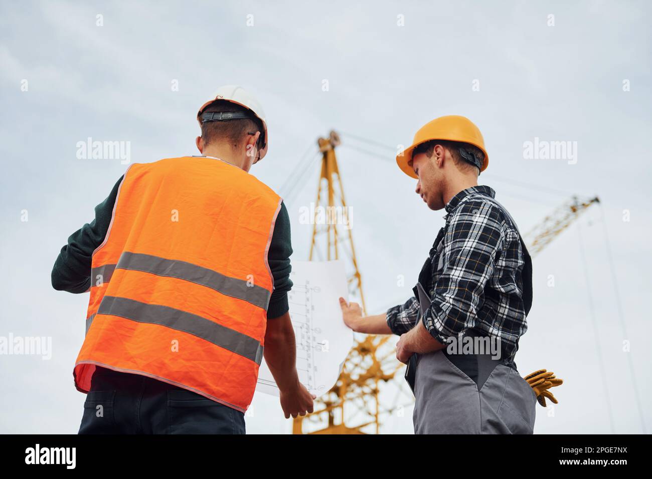 Using paper document with plan on it. Two construction workers in ...