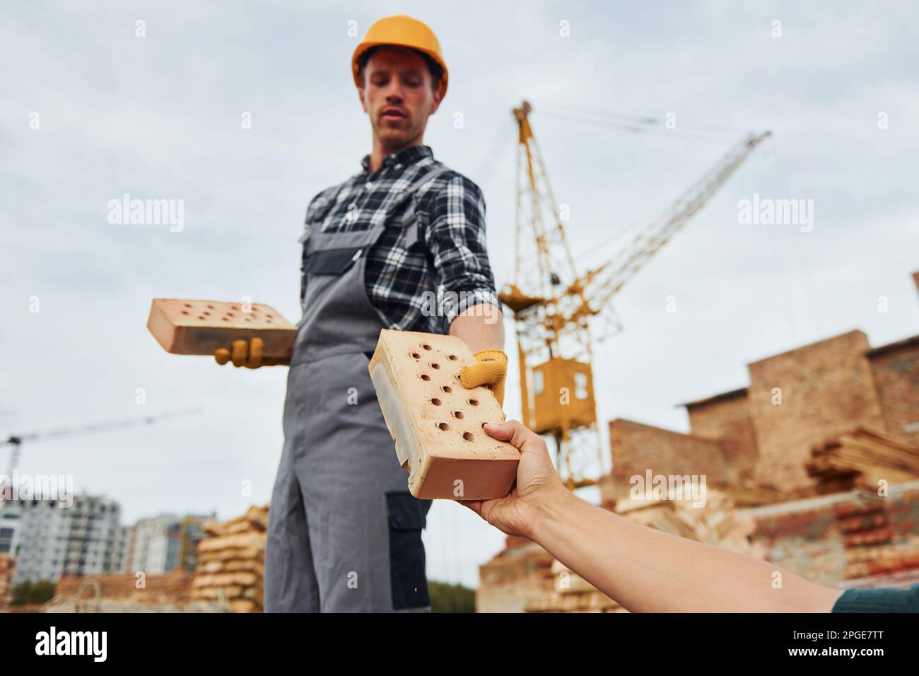 Takes brick from other guy. Construction worker in uniform and safety ...