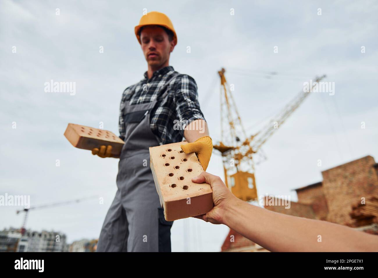 Takes brick from other guy. Construction worker in uniform and safety ...