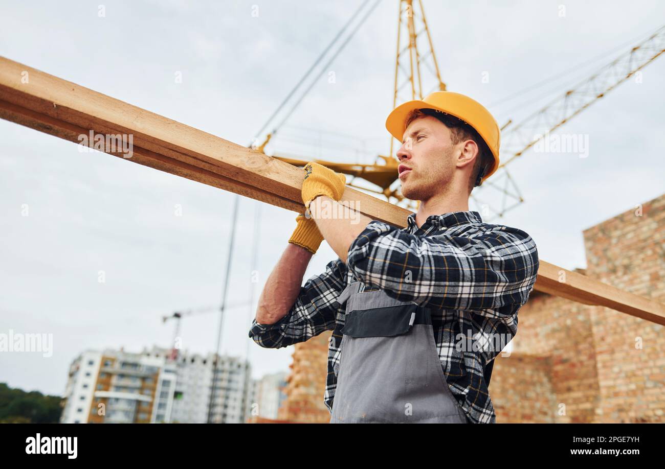 Transporting wooden boards. Construction worker in uniform and safety ...