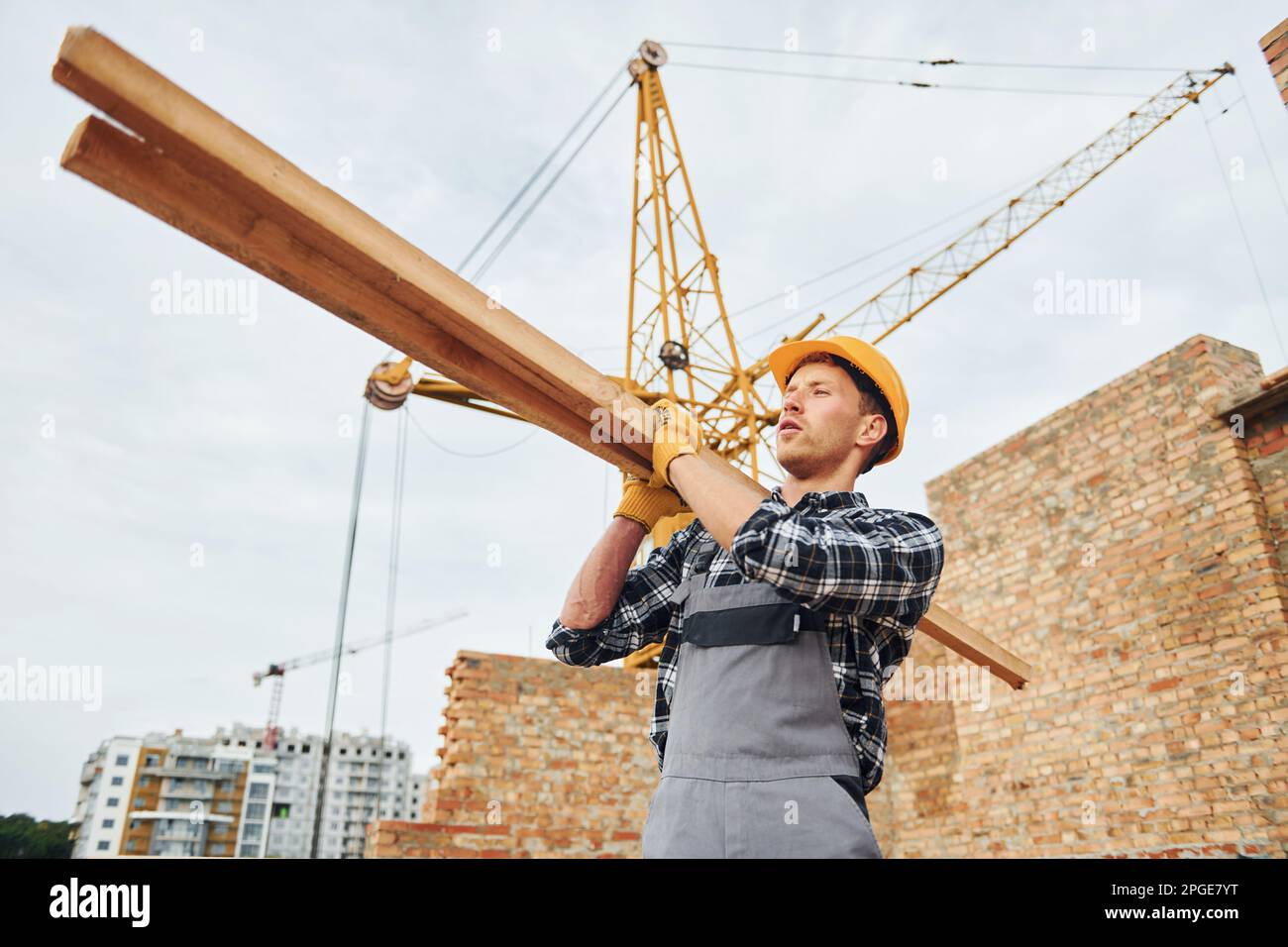 Transporting wooden boards. Construction worker in uniform and safety ...
