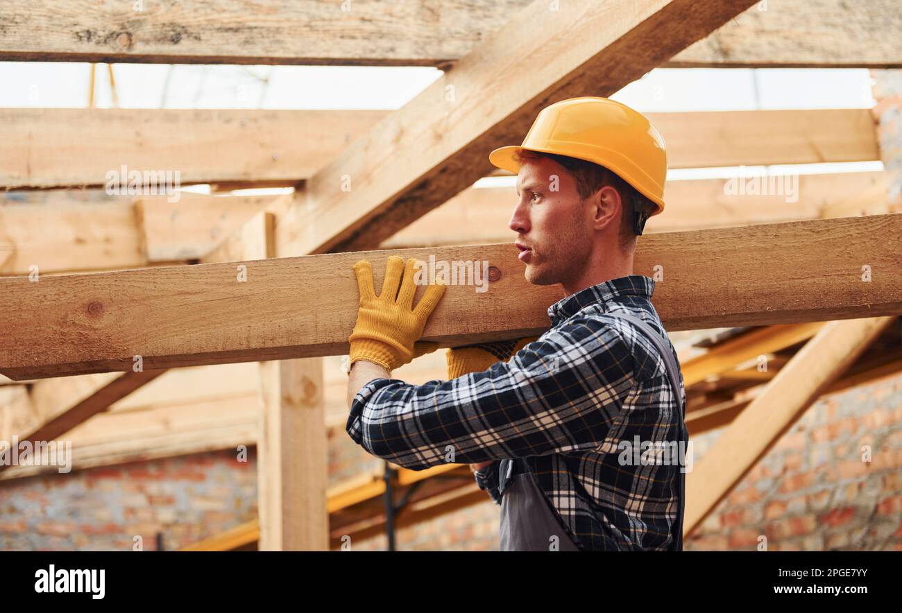 Transporting wooden boards. Construction worker in uniform and safety ...