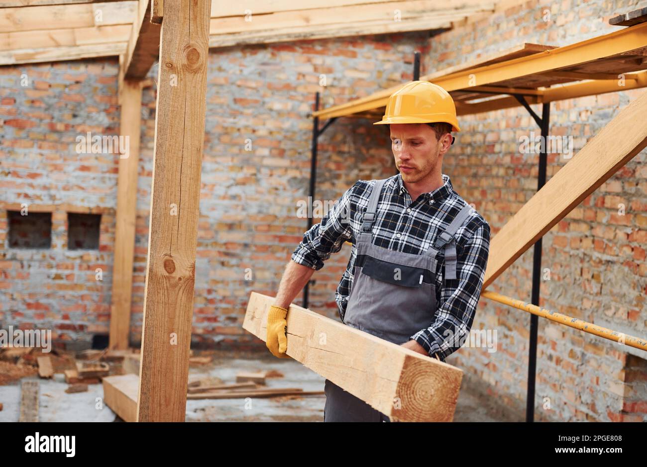 Transporting wooden boards. Construction worker in uniform and safety ...