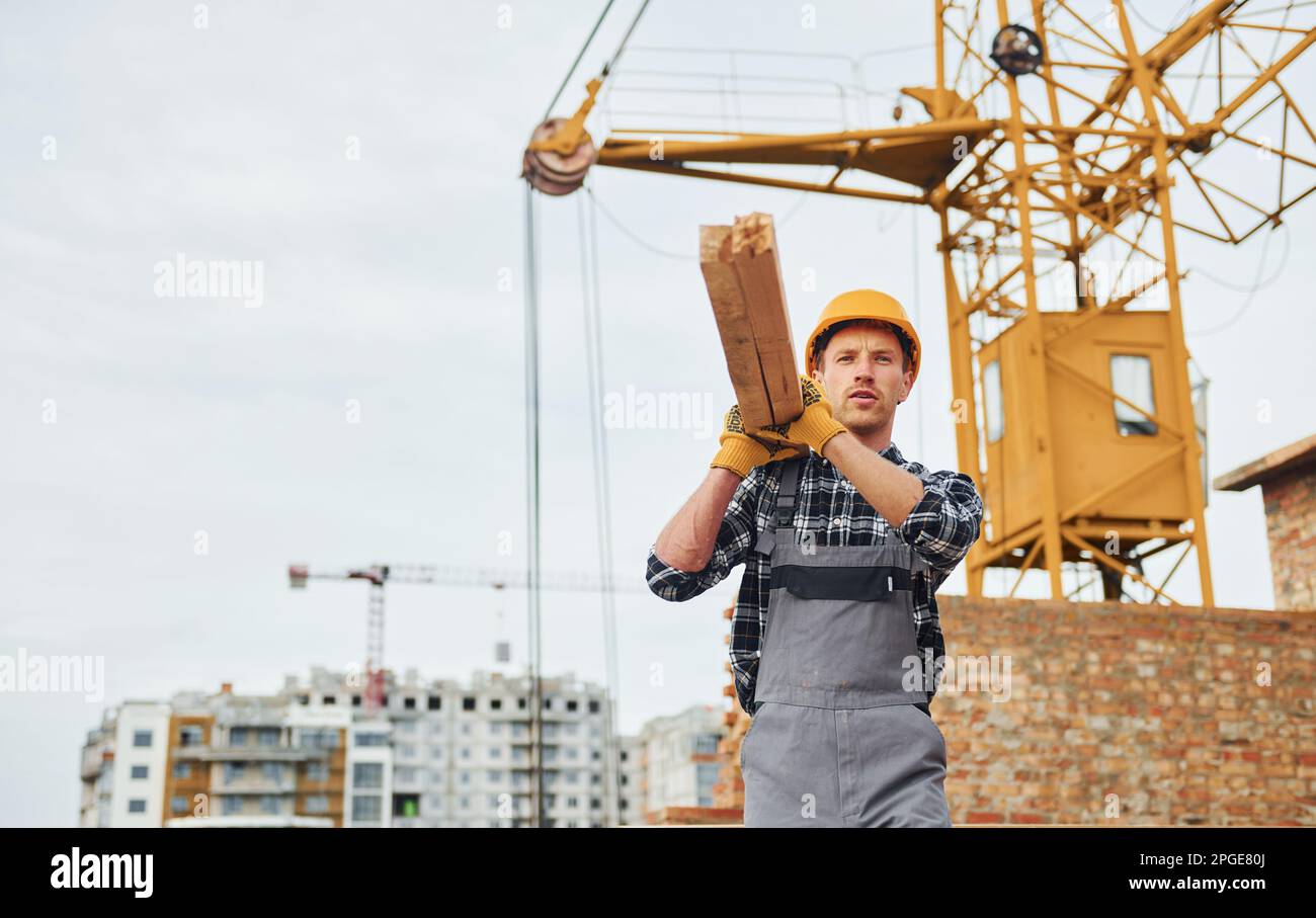 Transporting wooden boards. Construction worker in uniform and safety ...