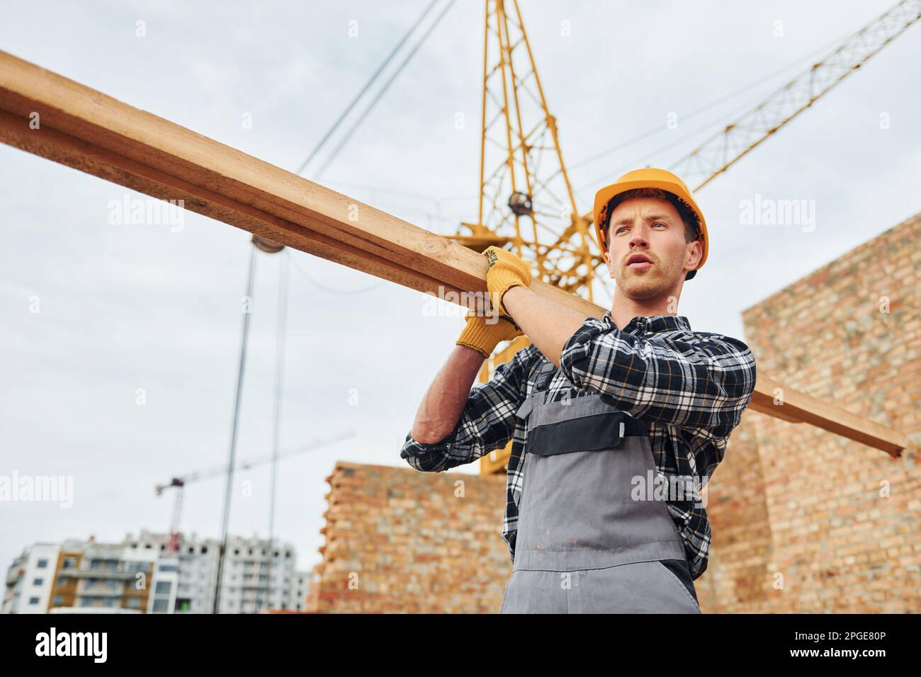 Transporting wooden boards. Construction worker in uniform and safety ...