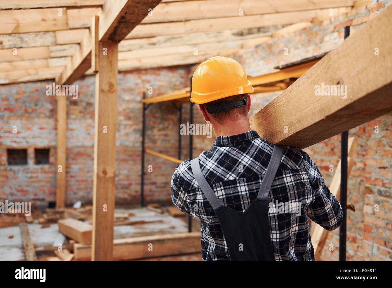 Transporting wooden boards. Construction worker in uniform and safety ...