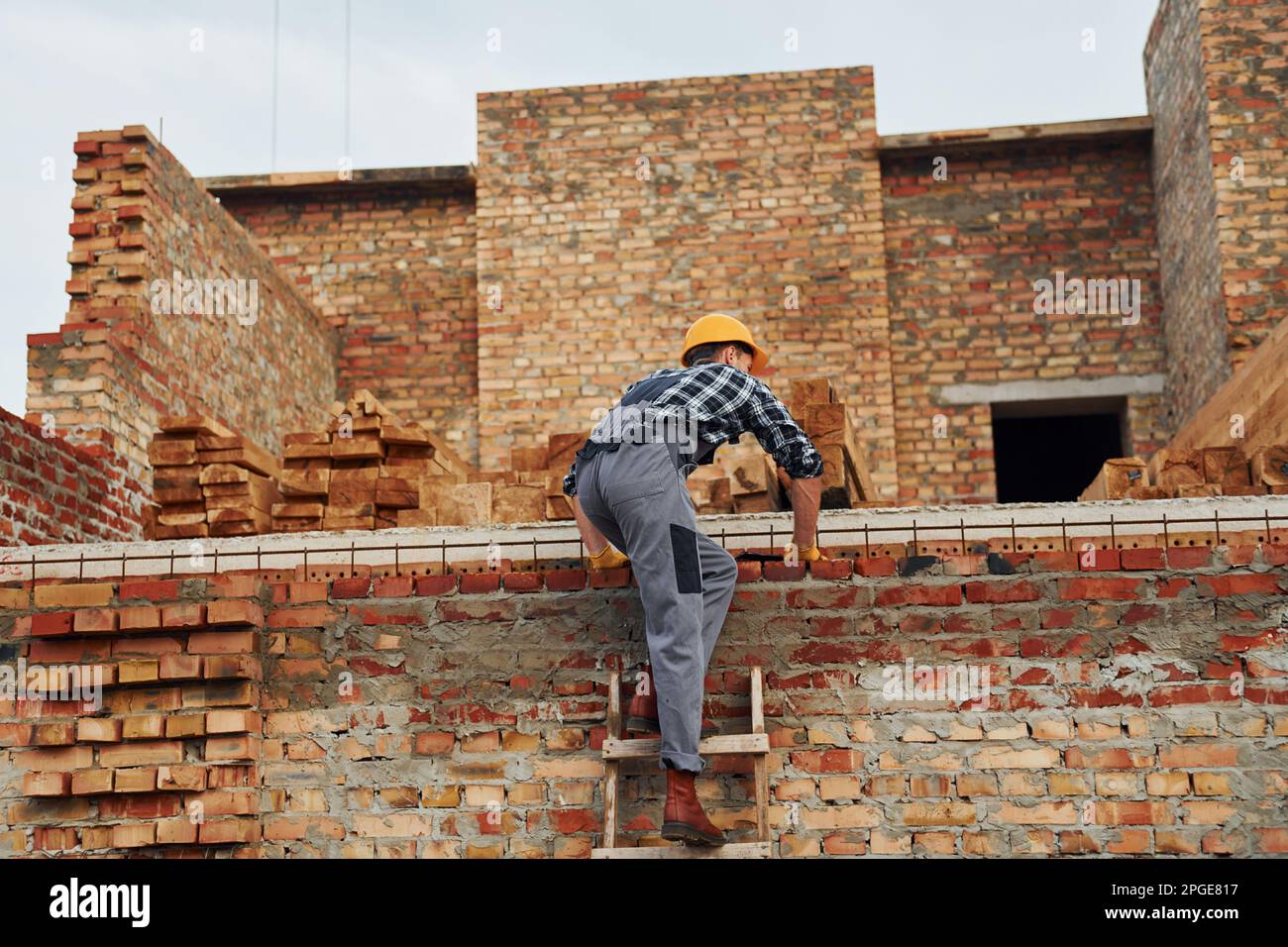 Climbs up. Construction worker in uniform and safety equipment have job ...
