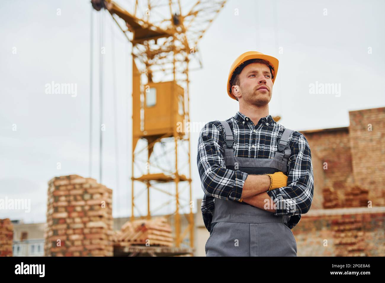With arms crossed. Construction worker in uniform and safety equipment ...