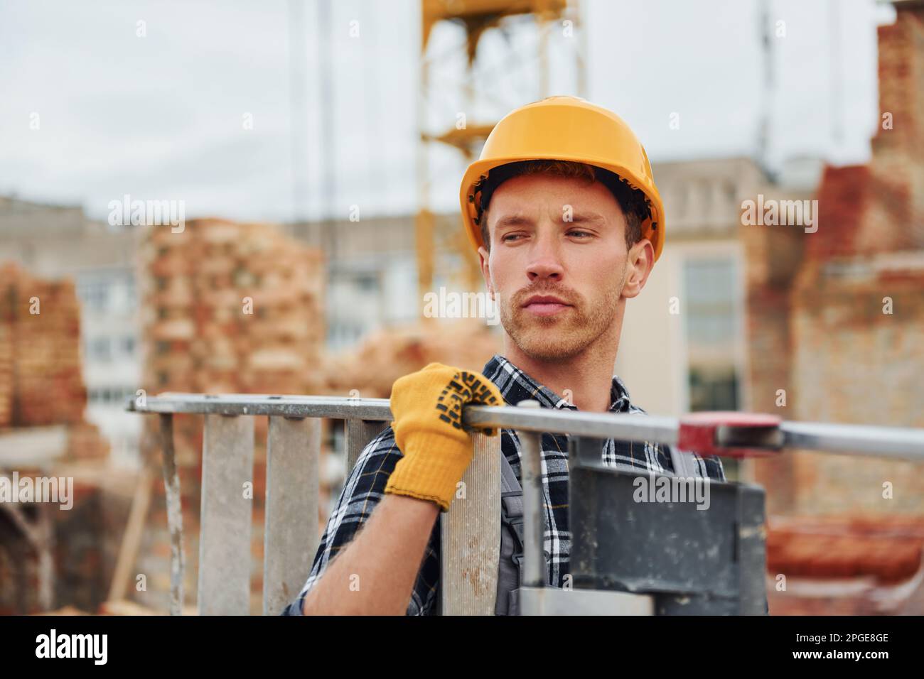 Ladder in hands. Construction worker in uniform and safety equipment ...