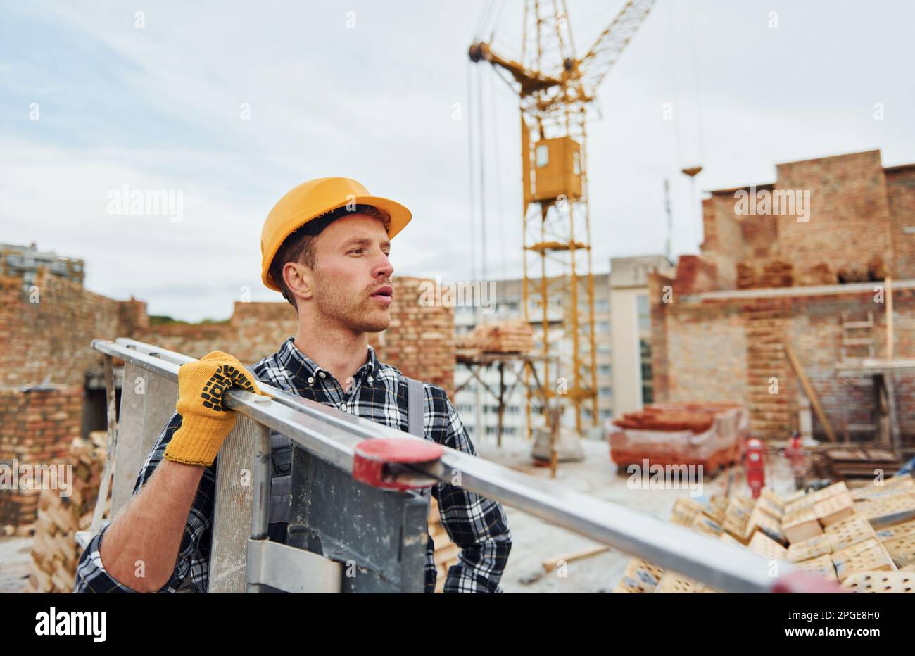 Ladder in hands. Construction worker in uniform and safety equipment ...
