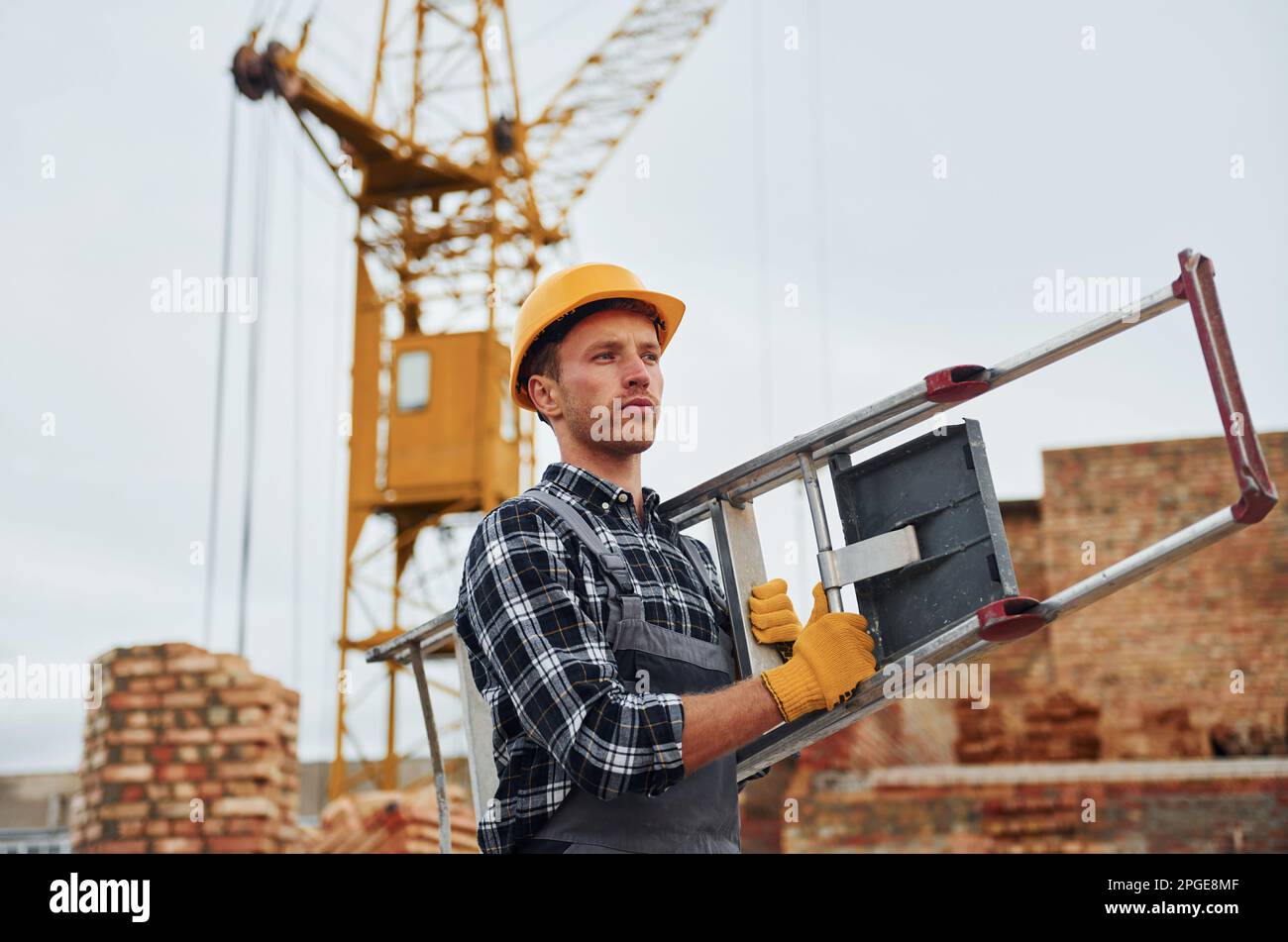 Ladder in hands. Construction worker in uniform and safety equipment ...