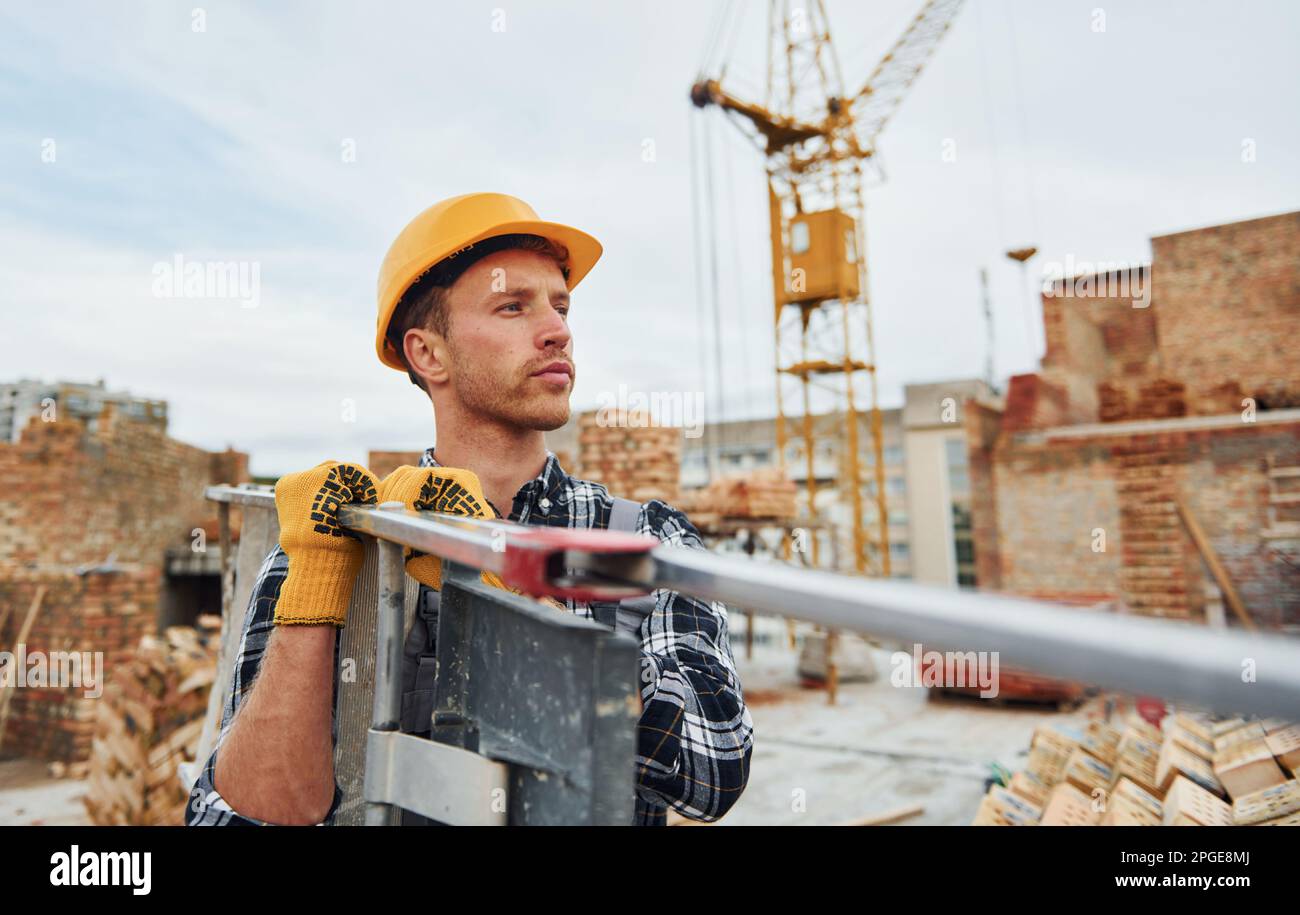Ladder in hands. Construction worker in uniform and safety equipment ...