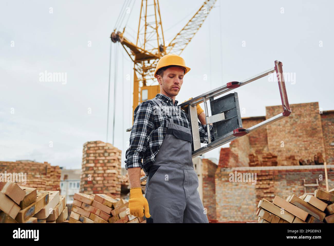 Ladder in hands. Construction worker in uniform and safety equipment ...