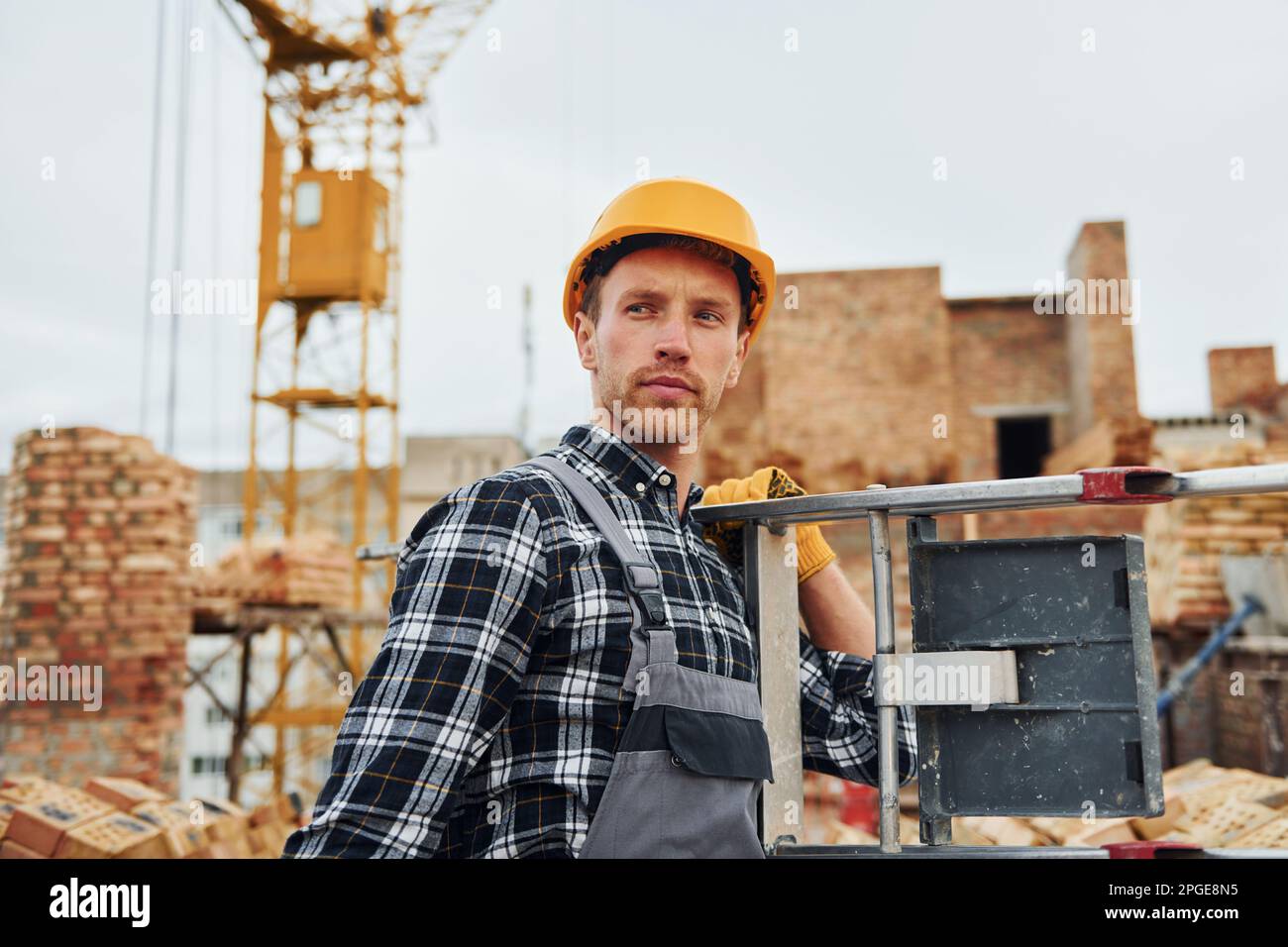 Ladder in hands. Construction worker in uniform and safety equipment ...