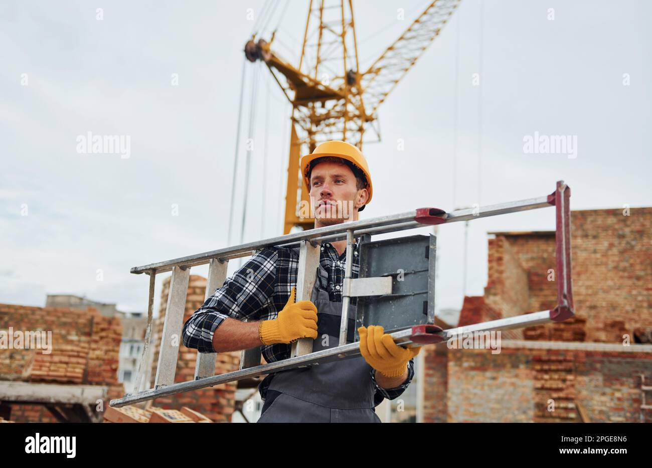 Ladder in hands. Construction worker in uniform and safety equipment ...