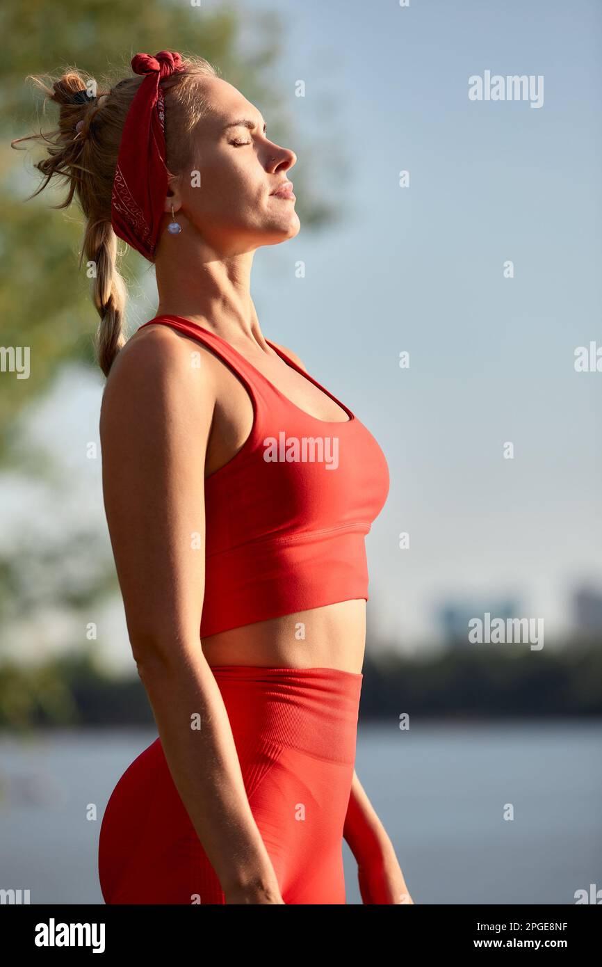 A woman does animal flow exercises in a red suit outdoors at dawn ...