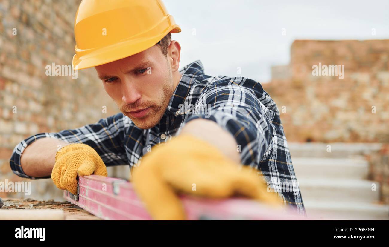 With level measuring tool. Construction worker in uniform and safety ...