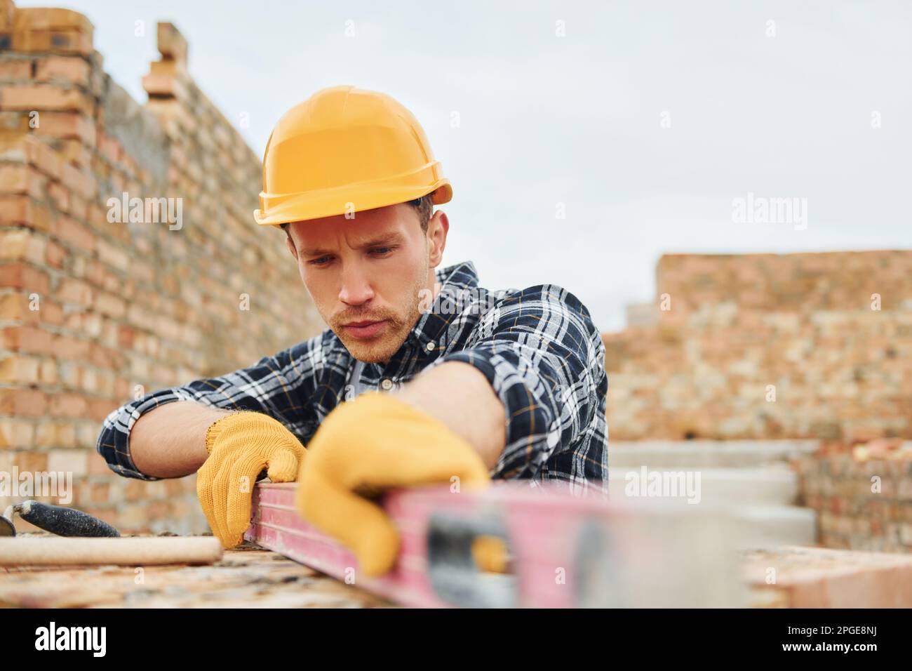 With level measuring tool. Construction worker in uniform and safety ...