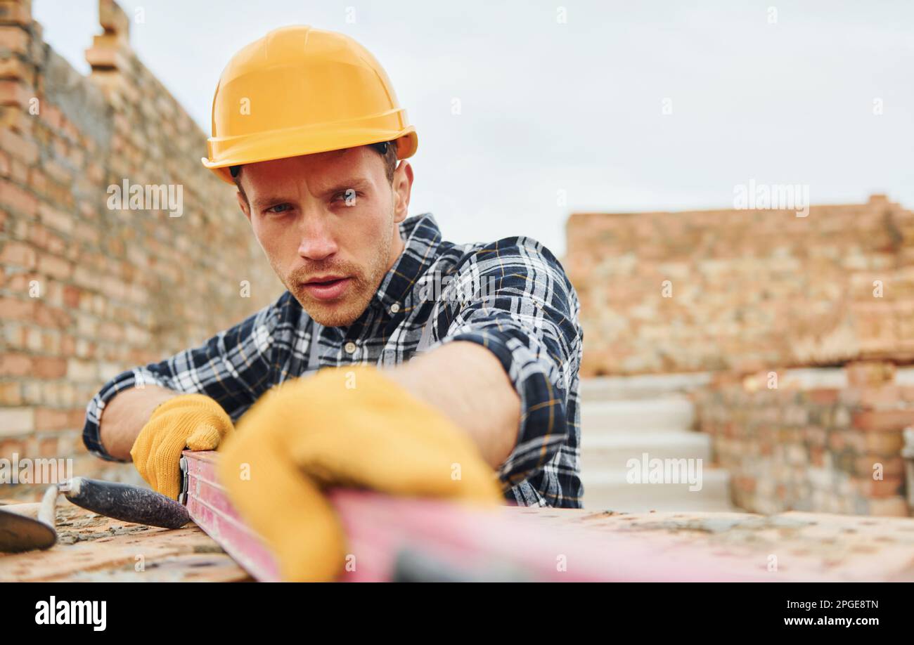 With level measuring tool. Construction worker in uniform and safety ...