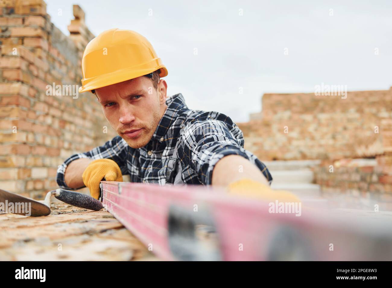 With level measuring tool. Construction worker in uniform and safety ...