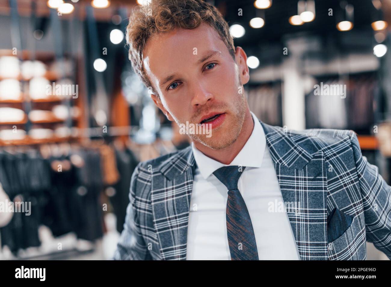 In jacket with tie. Young guy in modern store with new clothes. Elegant ...