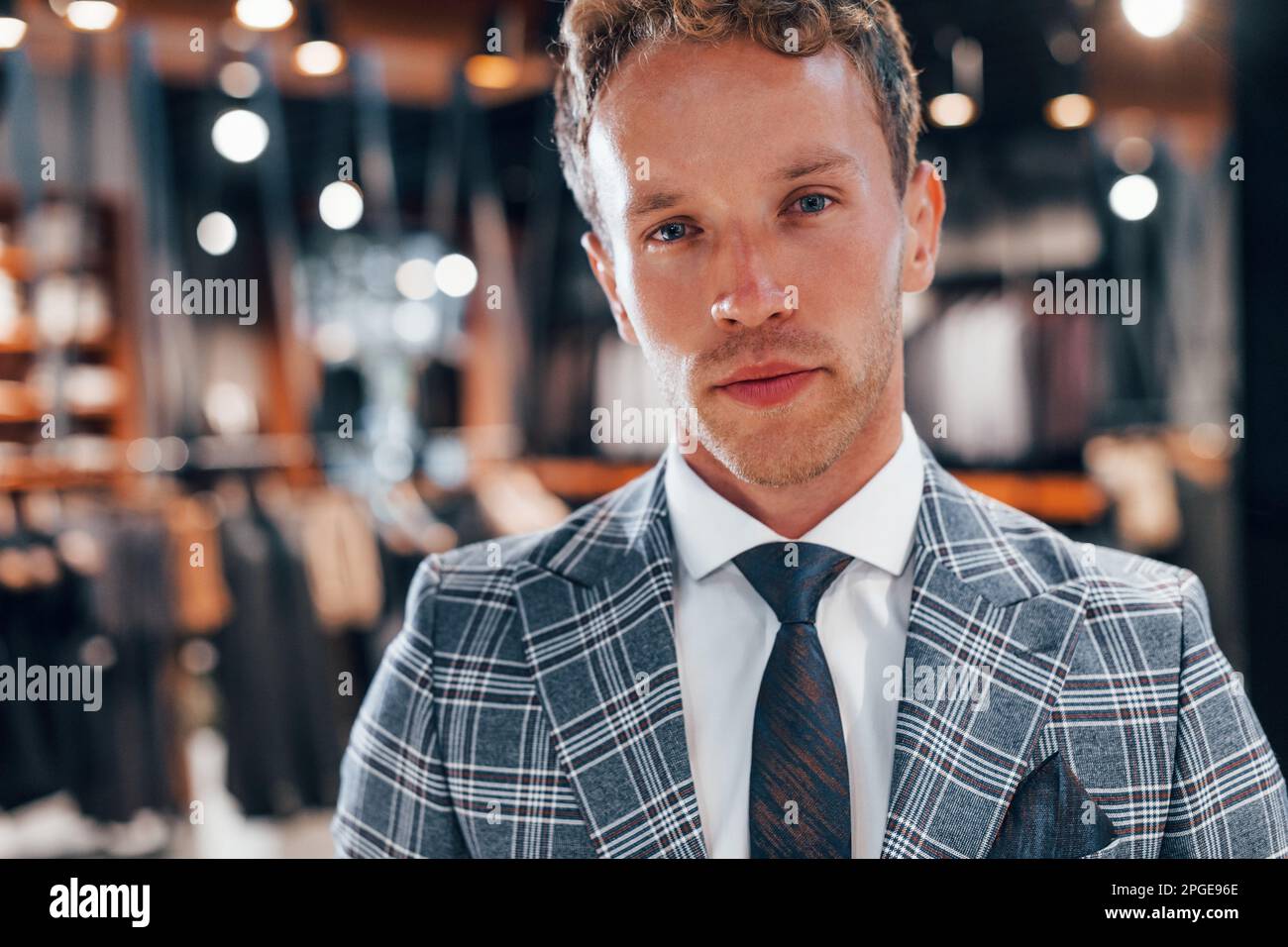 In jacket with tie. Young guy in modern store with new clothes. Elegant ...