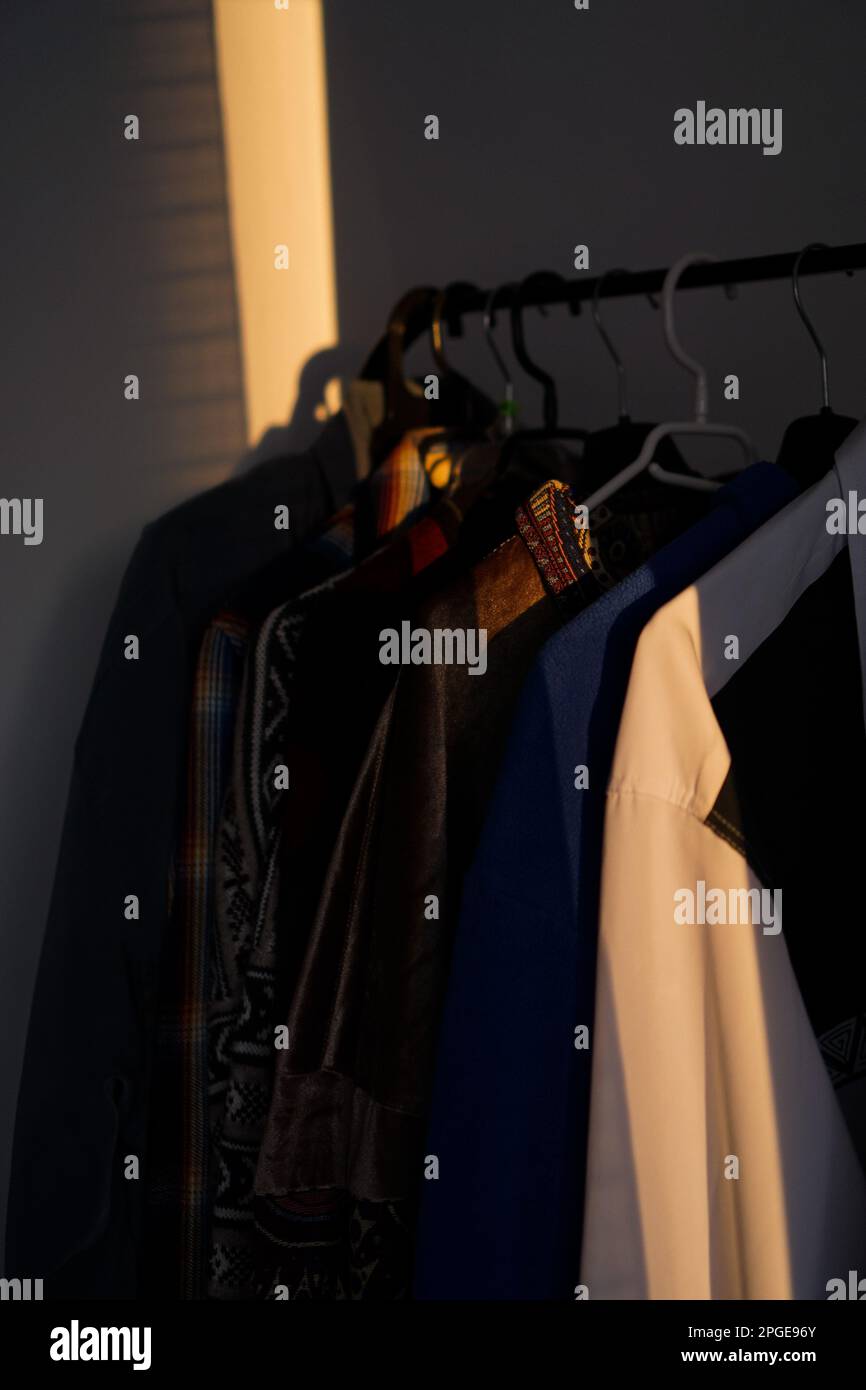 A row of clothing items, including shirts, hung on a rack Stock Photo ...