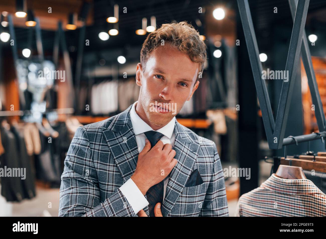 In jacket with tie. Young guy in modern store with new clothes. Elegant ...