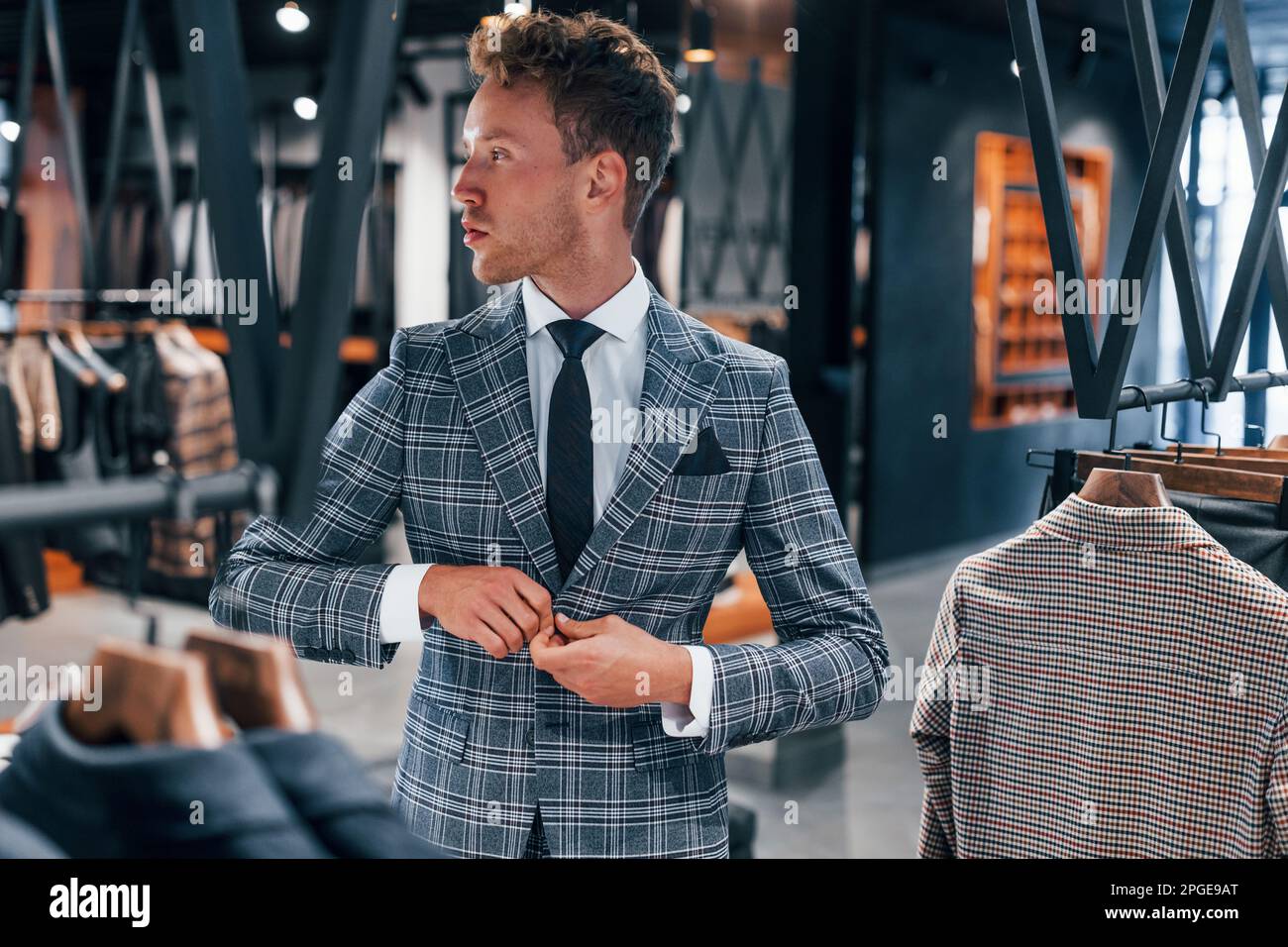 Tries on wear. Young guy in modern store with new clothes. Elegant ...