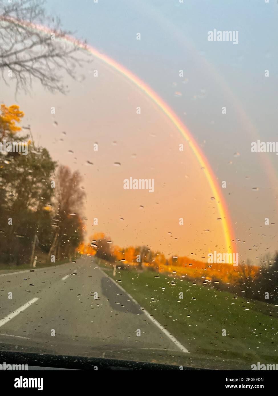 A close up view of rain droplets running down a car windshield, with ...
